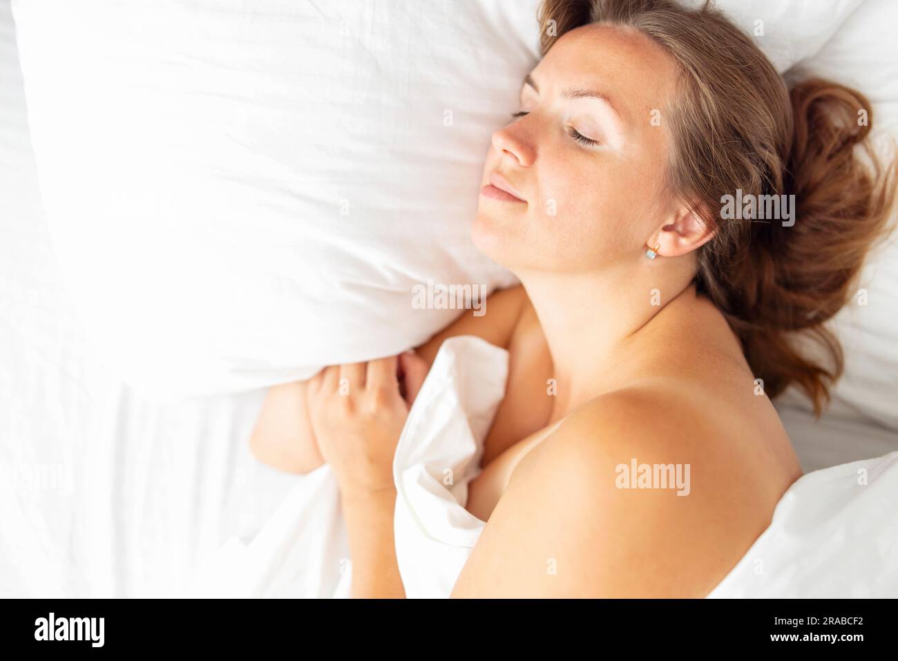 Beautiful young woman sleeps in the bedroom, lying on bed, top view ...