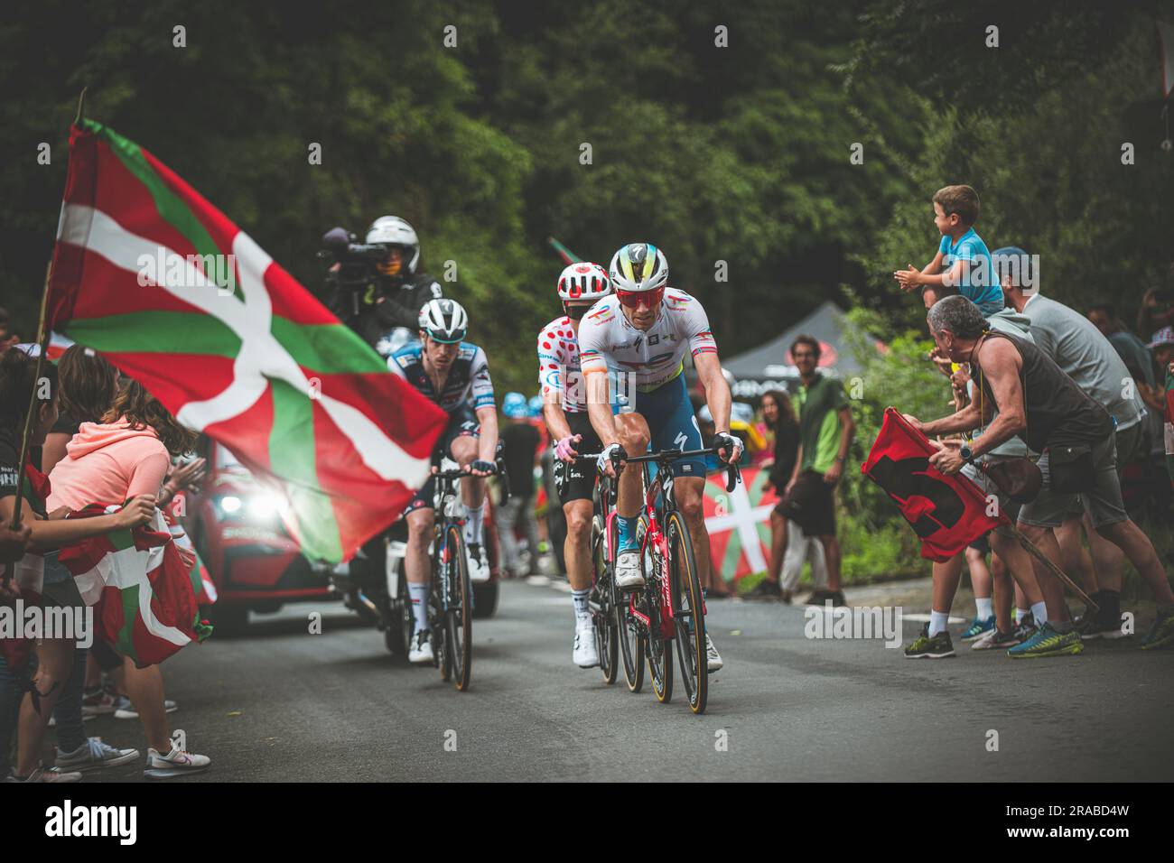 Cyclists surrounded by the Basque fans with the Ikurriña of the Tour de ...