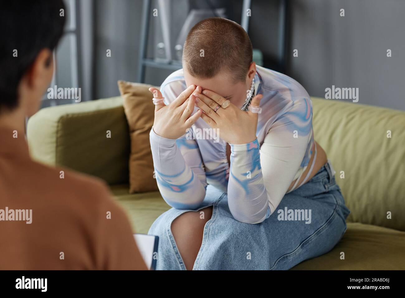 Young sad woman sitting on sofa and talking about her problems while ...