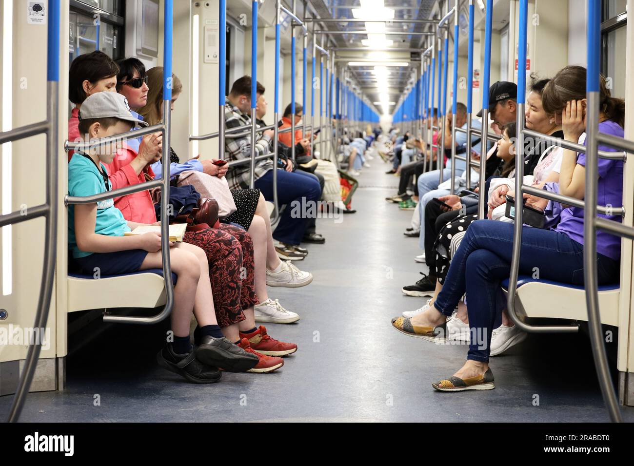 Crowd of people in a metro train in summer, passengers sits with ...