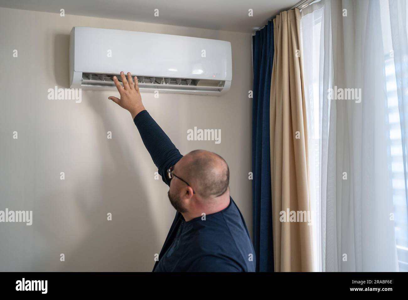 Man checks broken air conditioner at home. Male swipe hand near air ...