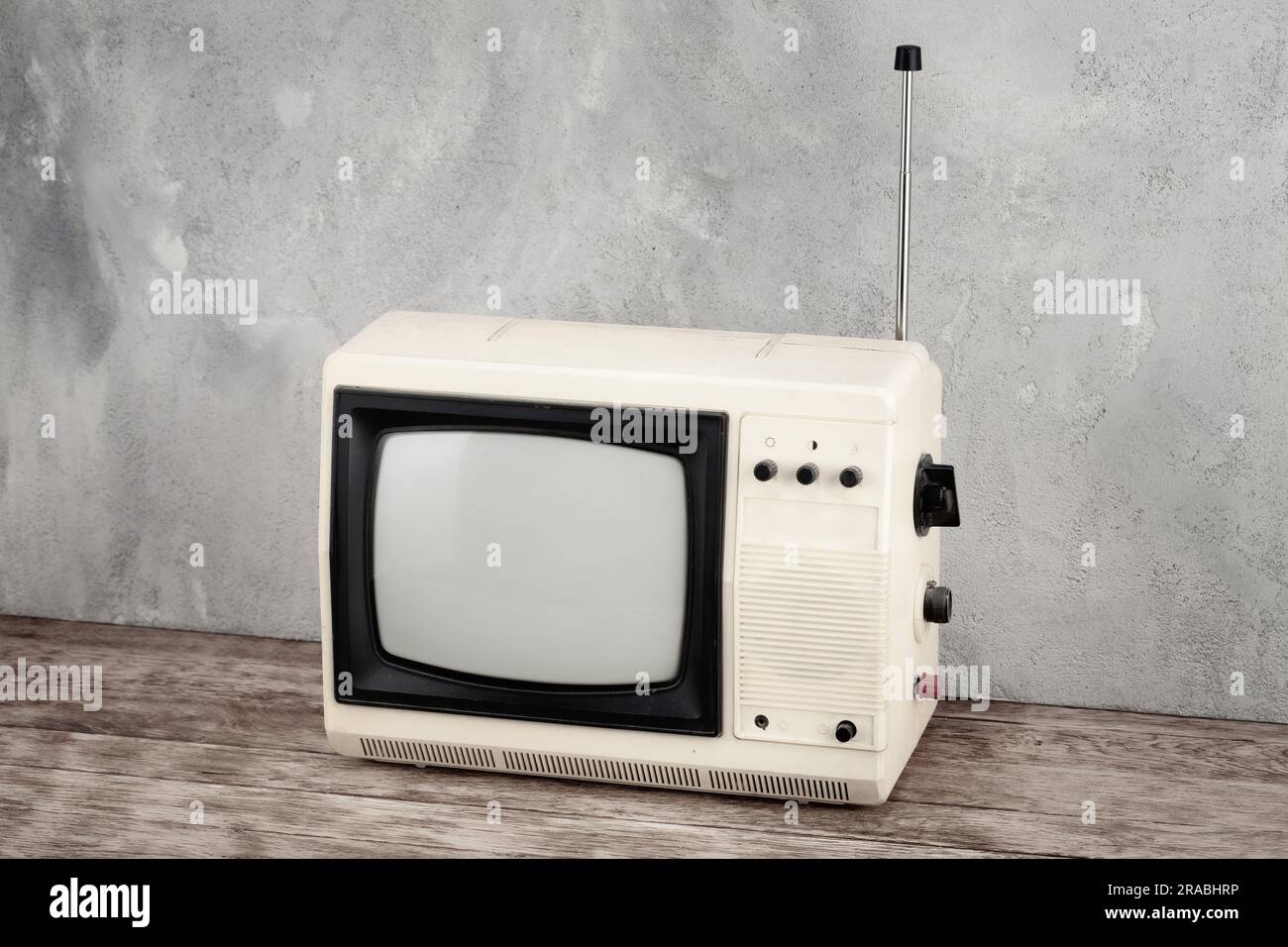 Vintage analog small TV set stand on wooden floor front grey concrete ...