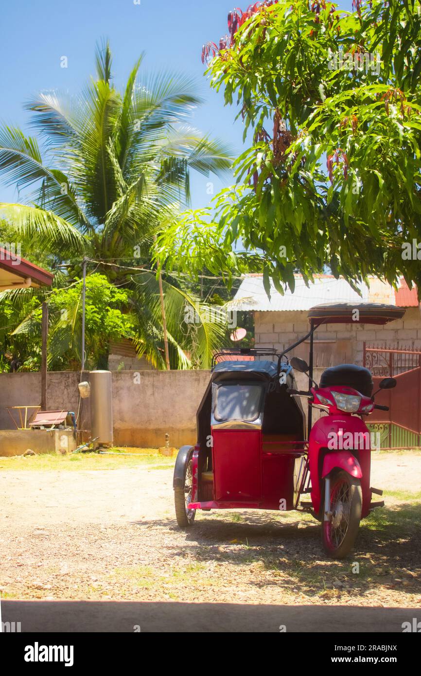 A red tricycle parked underneath a tree in Iba, Zambales, Philippines ...