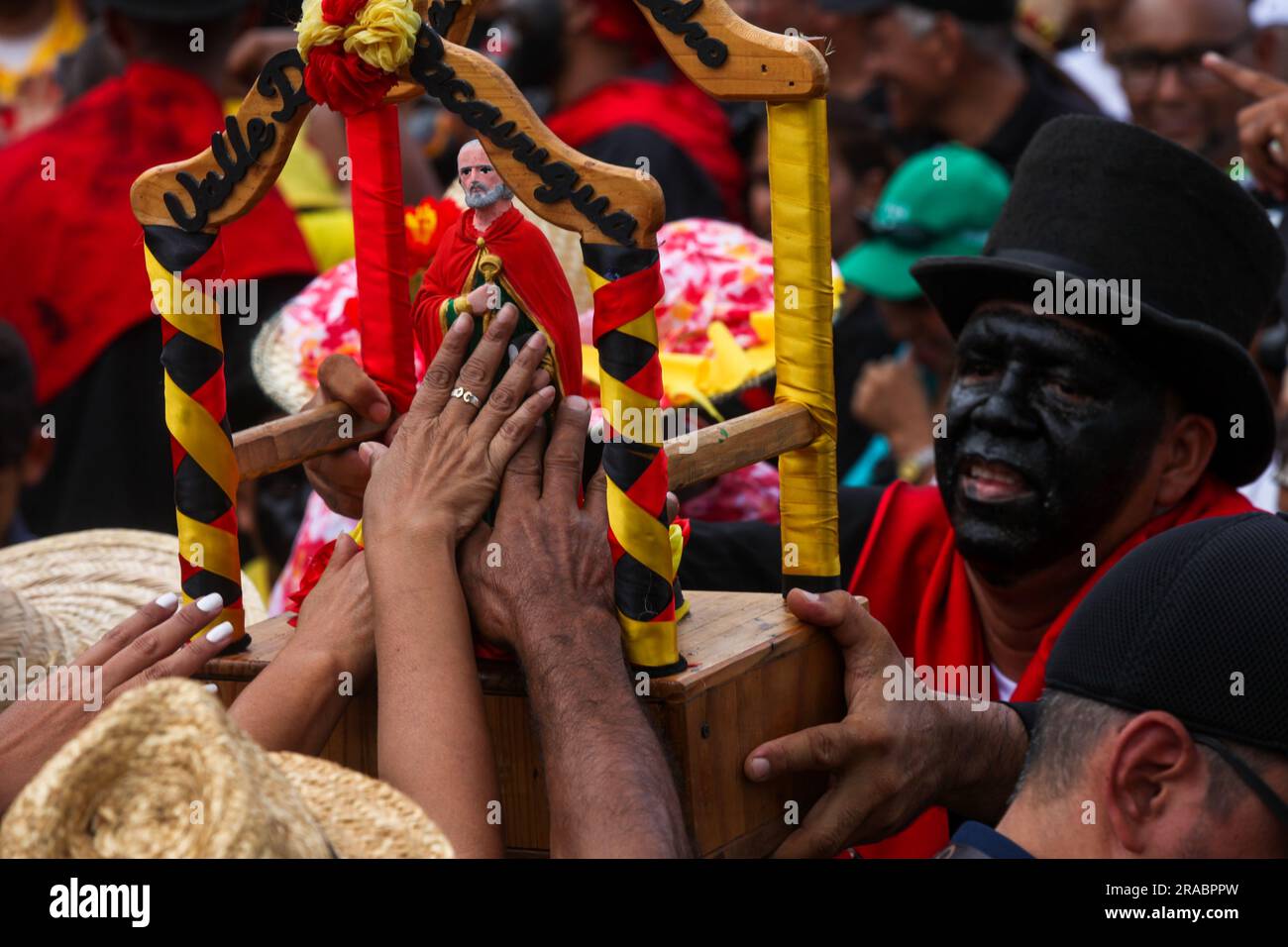 A San Pedro reveler holds the image of the saint, while it is touched by his devotees during the ...