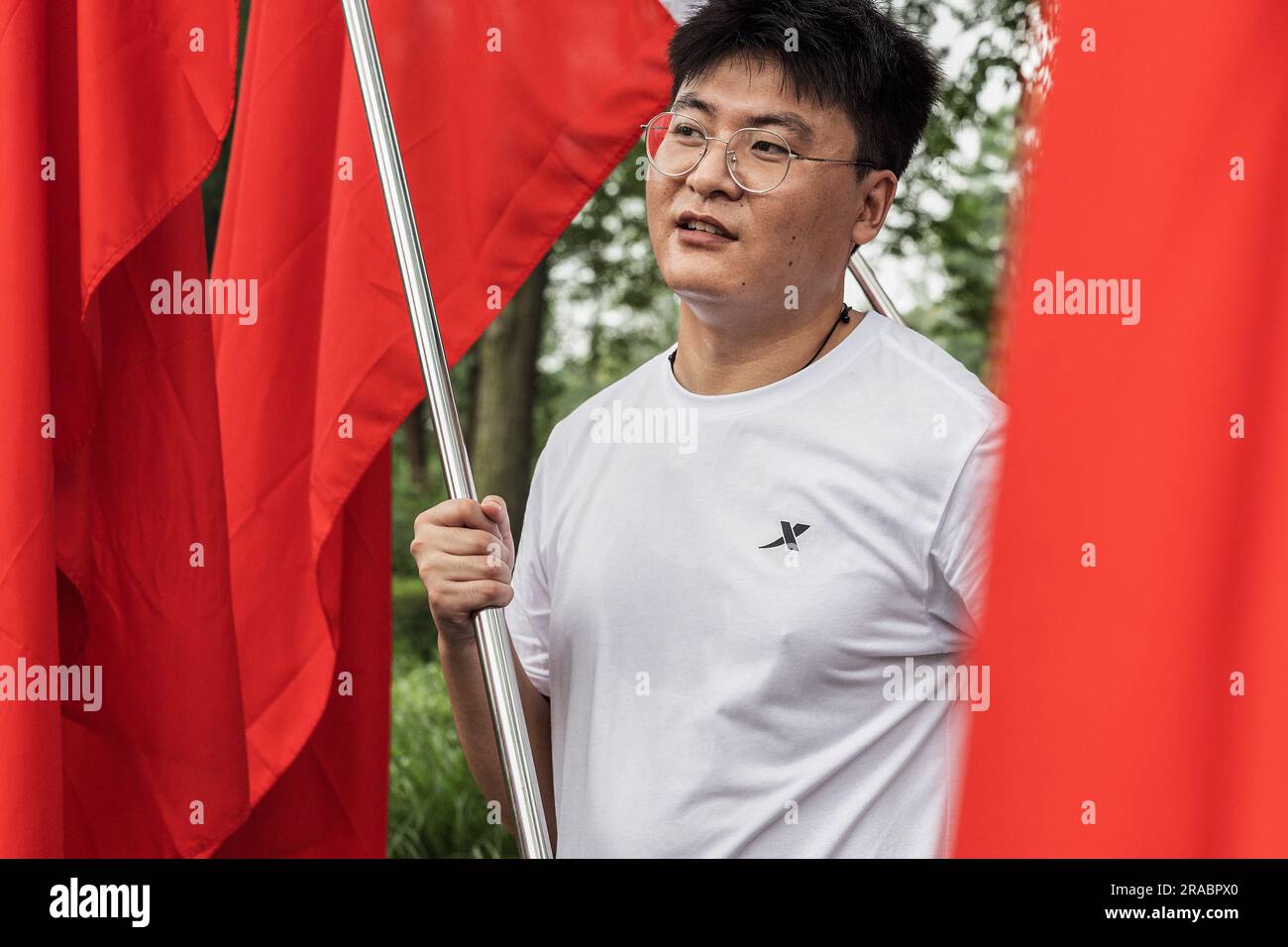 Wuhan, China. 01st July, 2023. A man holds a red flag during the 102nd ...