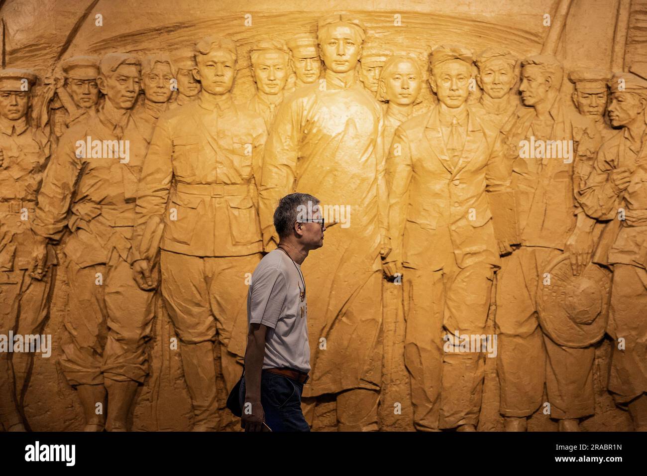 Wuhan, China. 01st July, 2023. A man walks past a wall with reliefs of ...