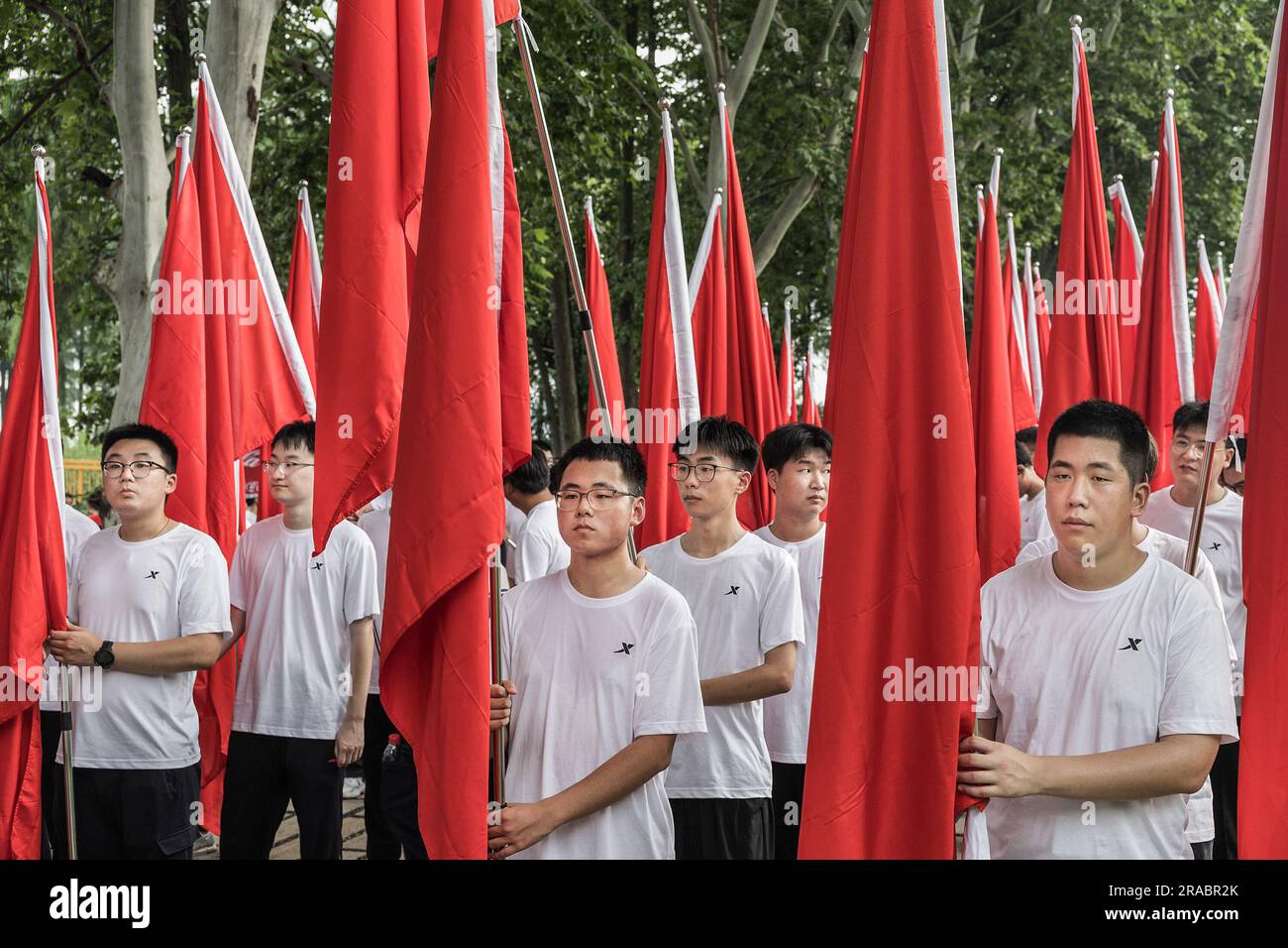 Wuhan, China. 01st July, 2023. Young men hold red flags during the ...