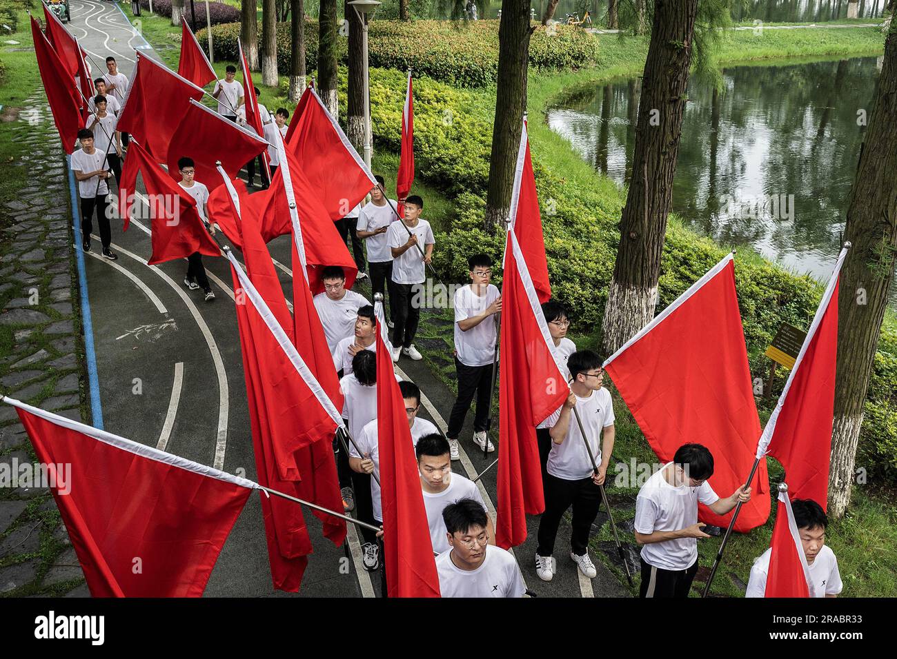 Wuhan, China. 01st July, 2023. Young men hold red flags during the ...