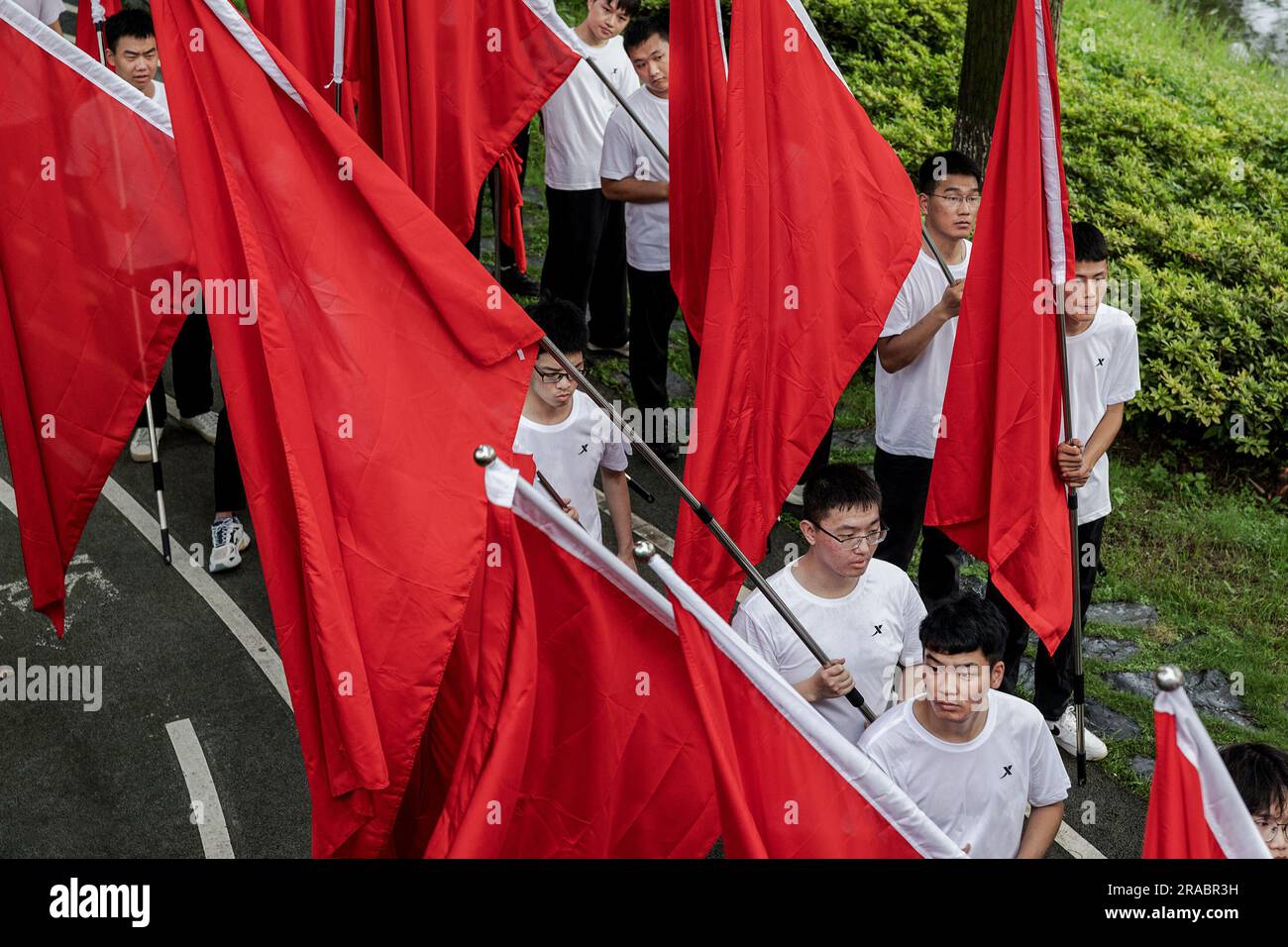 Wuhan, China. 01st July, 2023. Young men hold red flags during the ...