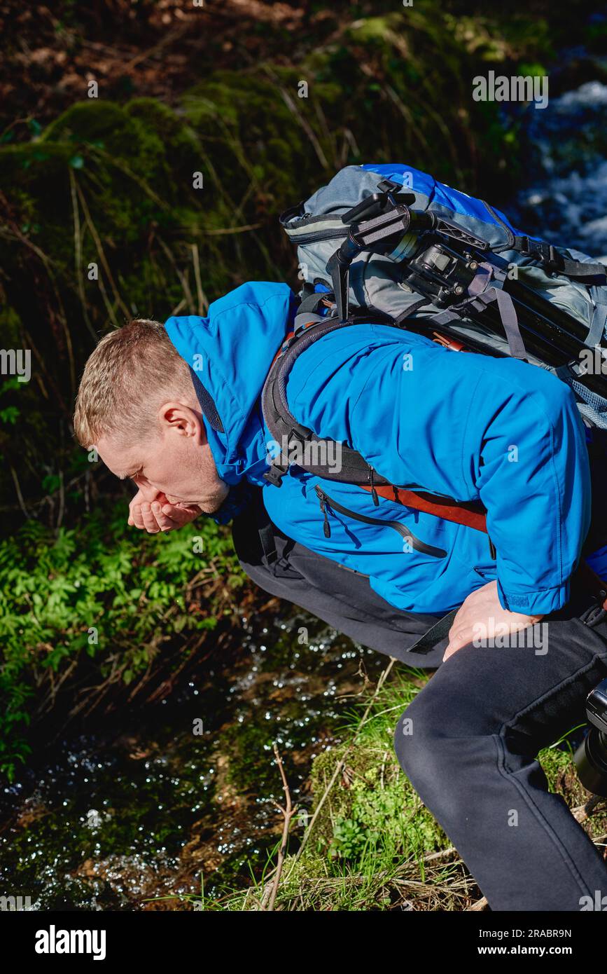 Hiker drinking stream water in mountain. Adult man drinking water from ...