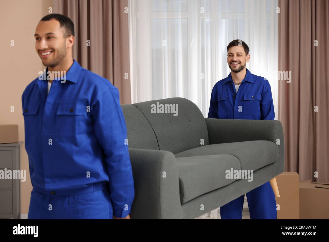 Male movers carrying sofa in new house Stock Photo - Alamy