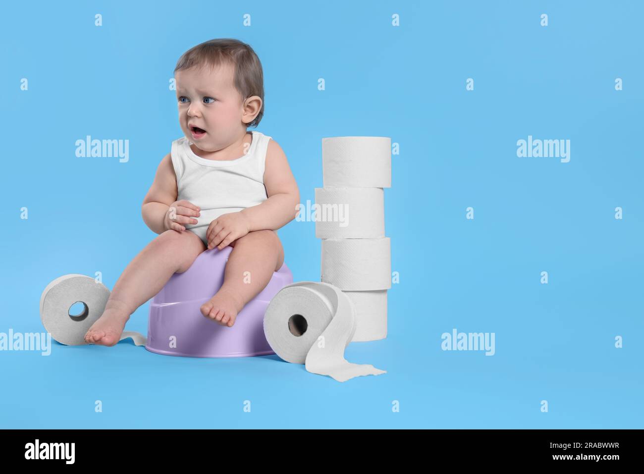 Little child sitting on baby potty and stack of toilet paper rolls ...