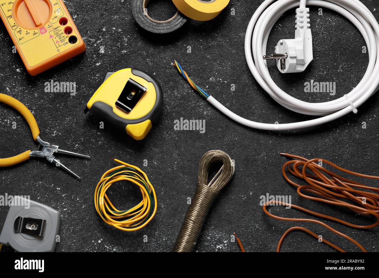 Different electrical wires and tools on black textured table, flat lay ...