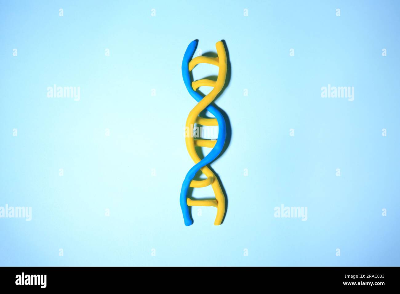 DNA molecule model made of colorful plasticine on light blue background ...