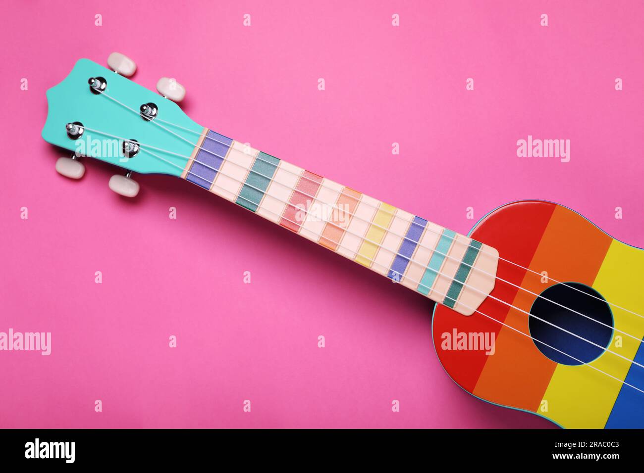 Colorful ukulele on pink background, top view. String musical ...