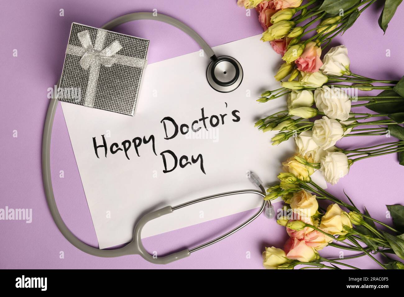 Card with phrase Happy Doctor's Day, stethoscope, gift box and flowers ...