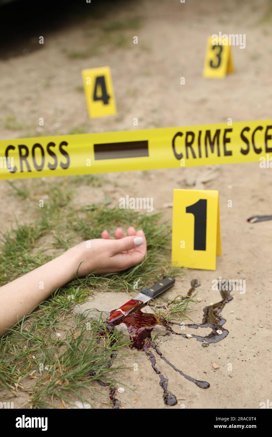 Crime scene with dead woman's body, markers, bloody knife and yellow ...