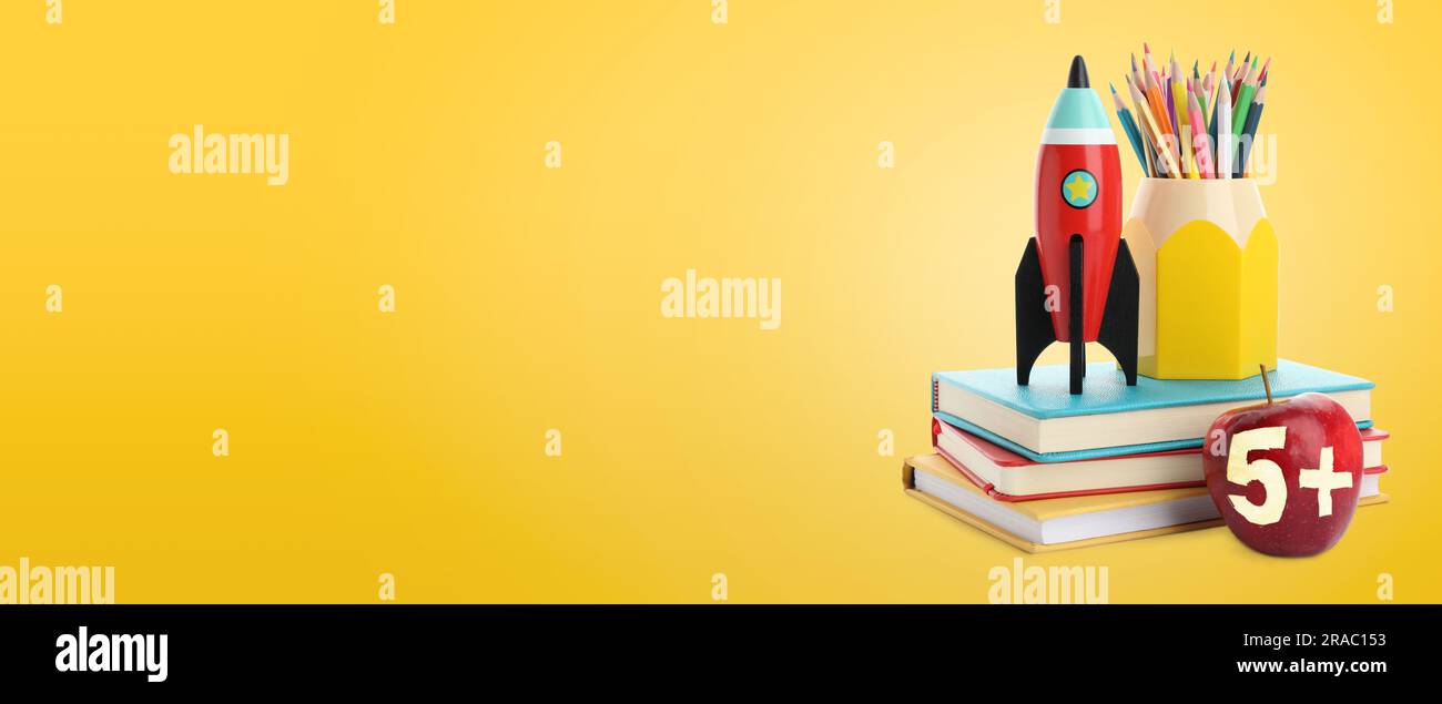 Apple with carved number five as grade. Bright toy rocket and school ...