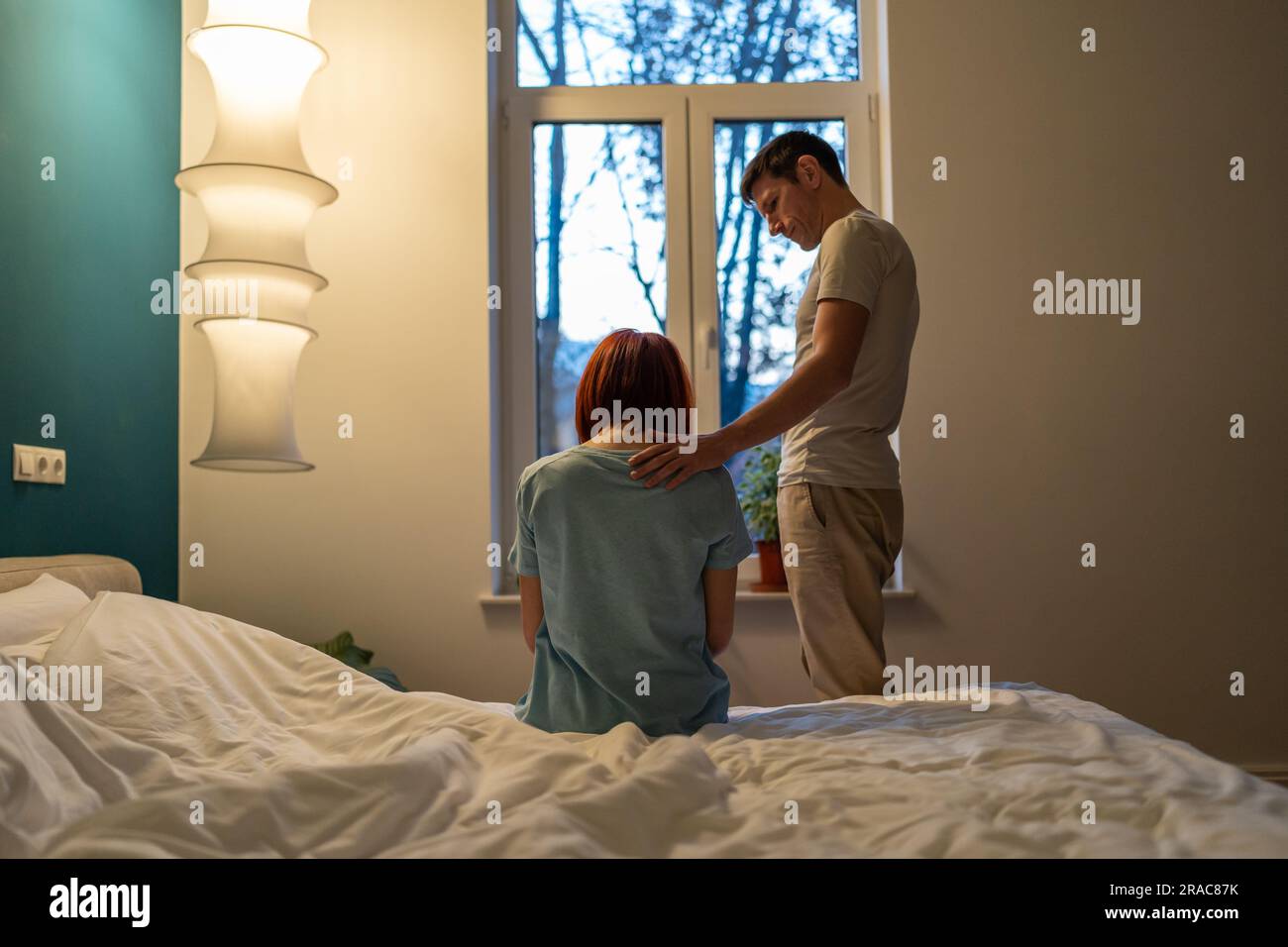 Family support. Sad woman sits on bed near standing caring loving man ...
