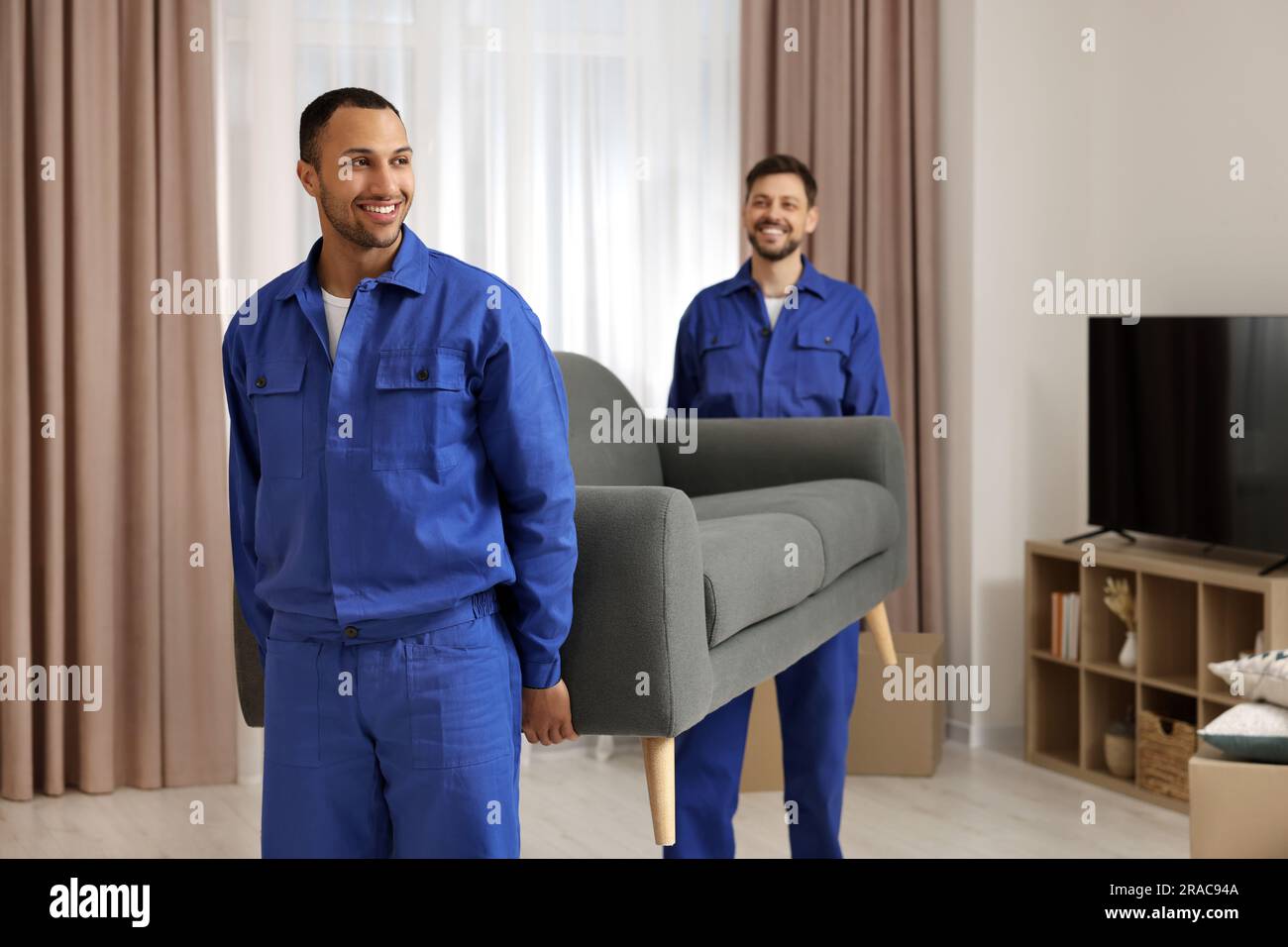 Male movers carrying sofa in new house Stock Photo - Alamy