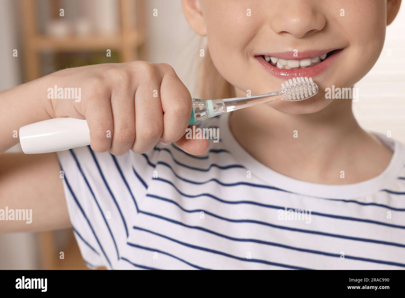 Little girl brushing her teeth with electric toothbrush in bathroom ...