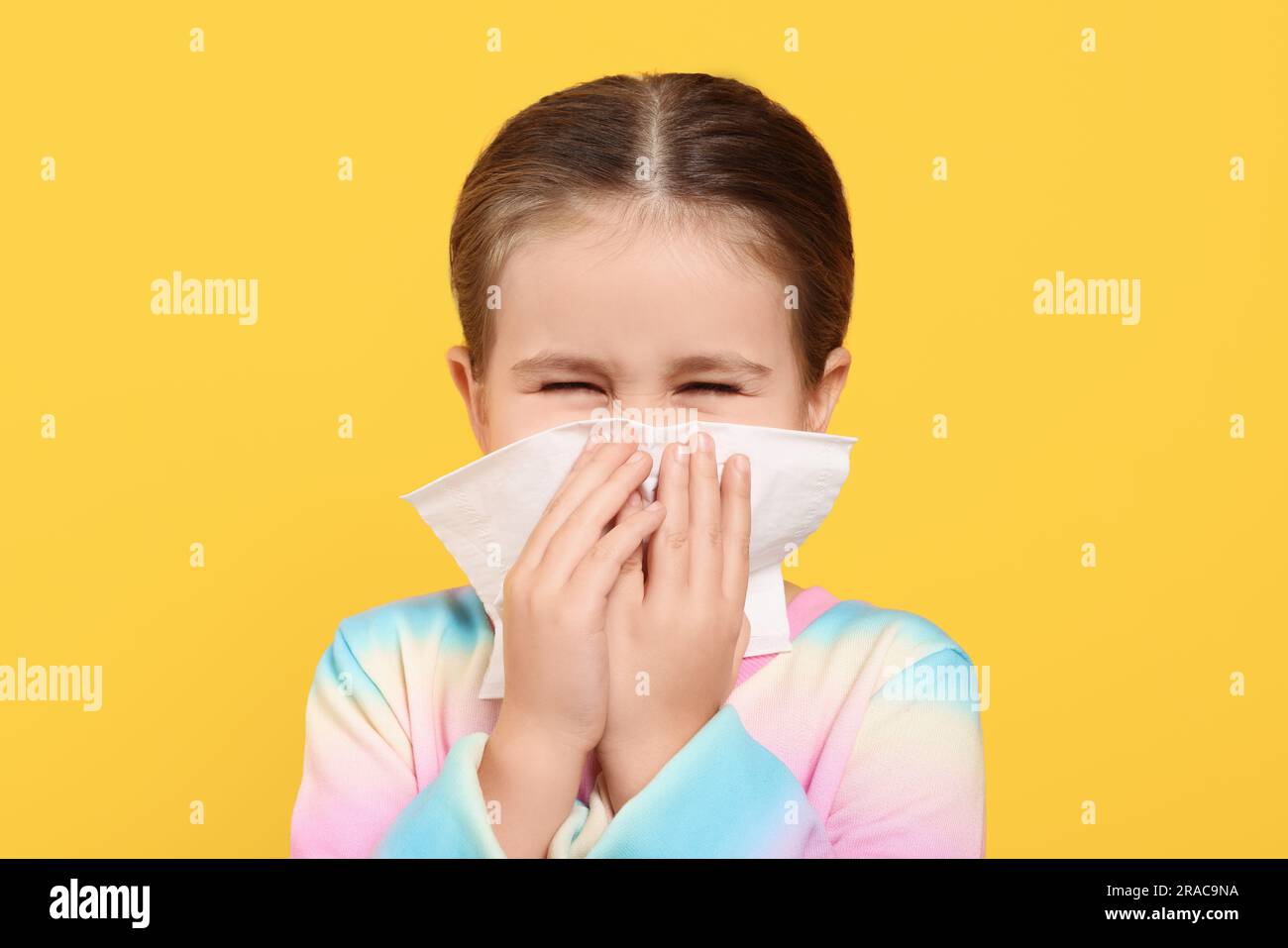Girl blowing nose in tissue on orange background. Cold symptoms Stock ...