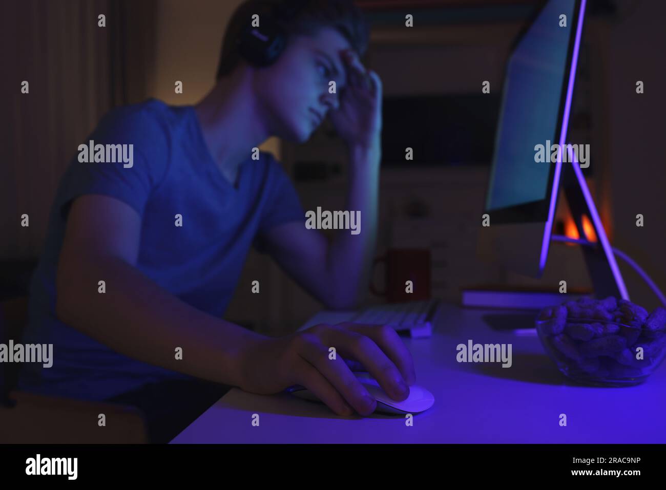 Teenage boy using computer in room at night, focus on hand. Internet ...