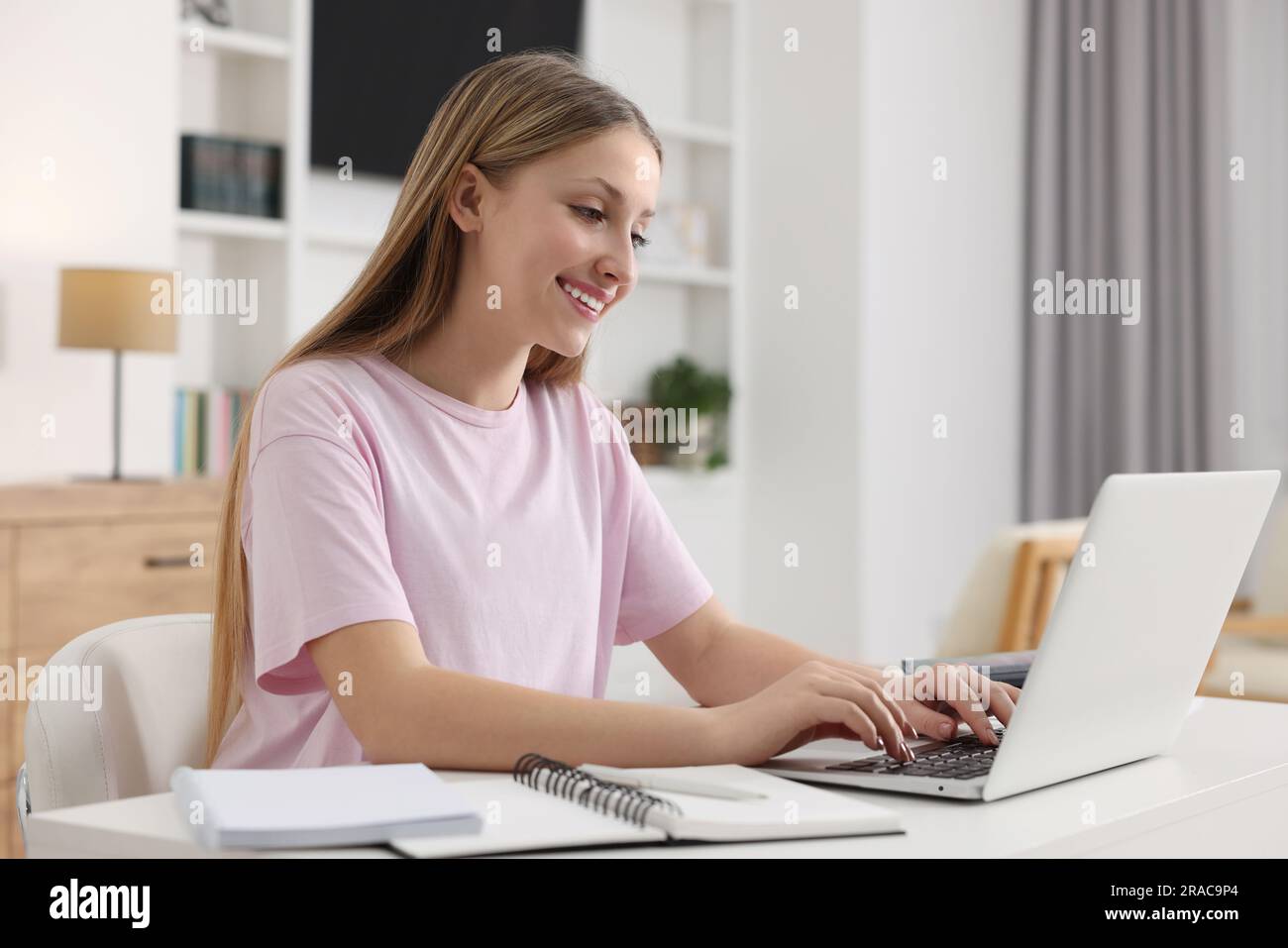 Online learning. Teenage girl typing on laptop at table Stock Photo - Alamy
