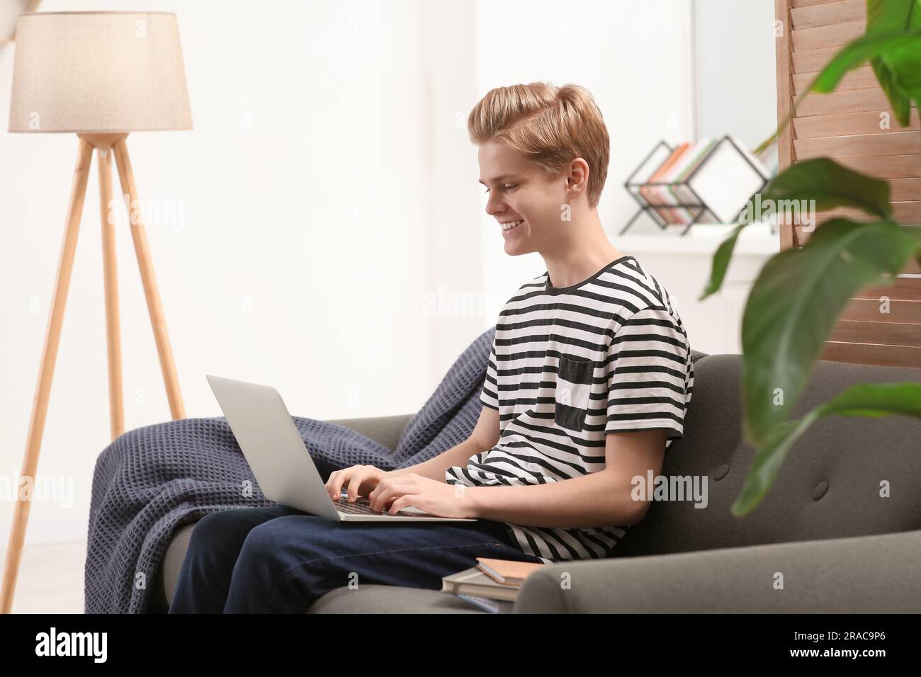Online learning. Smiling teenage boy typing on laptop at home Stock ...