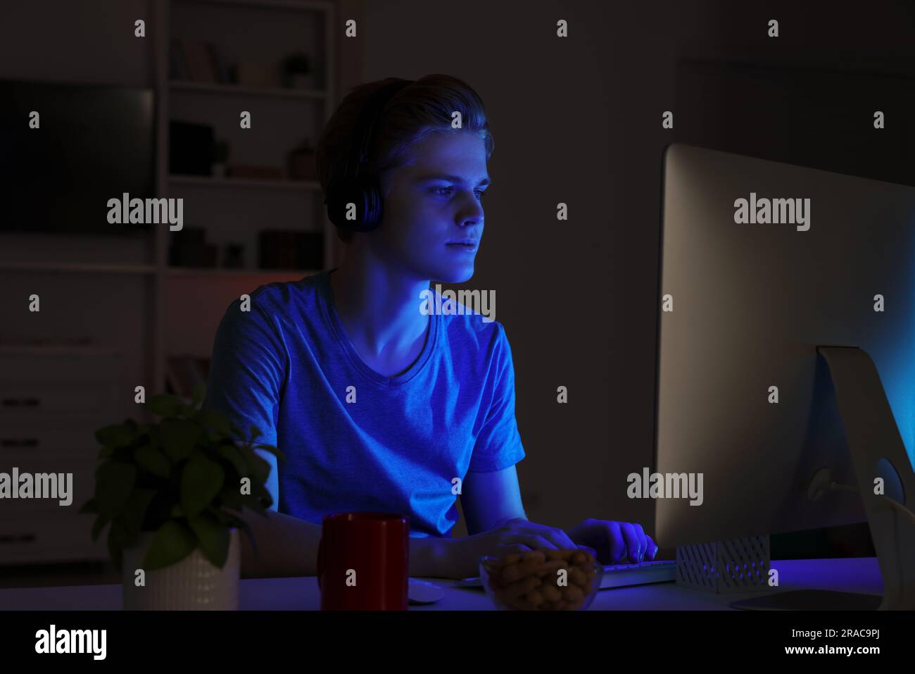 Teenage boy using computer in bedroom at night. Internet addiction ...