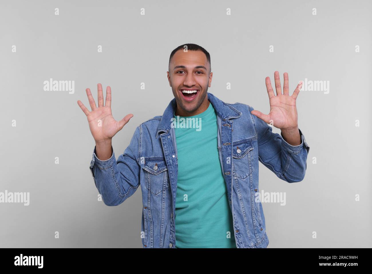 Man giving high five with both hands on grey background Stock Photo - Alamy