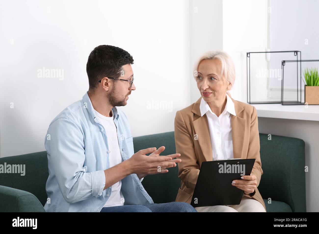 Woman having conversation with man on sofa in office. Manager ...