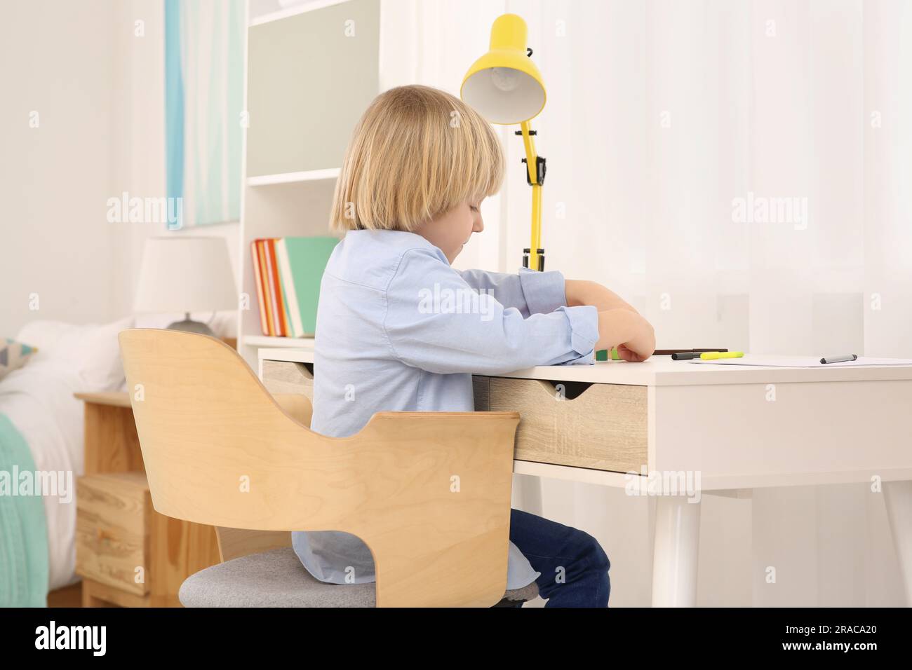 Cute little boy playing with colorful wooden cubes at desk in room ...