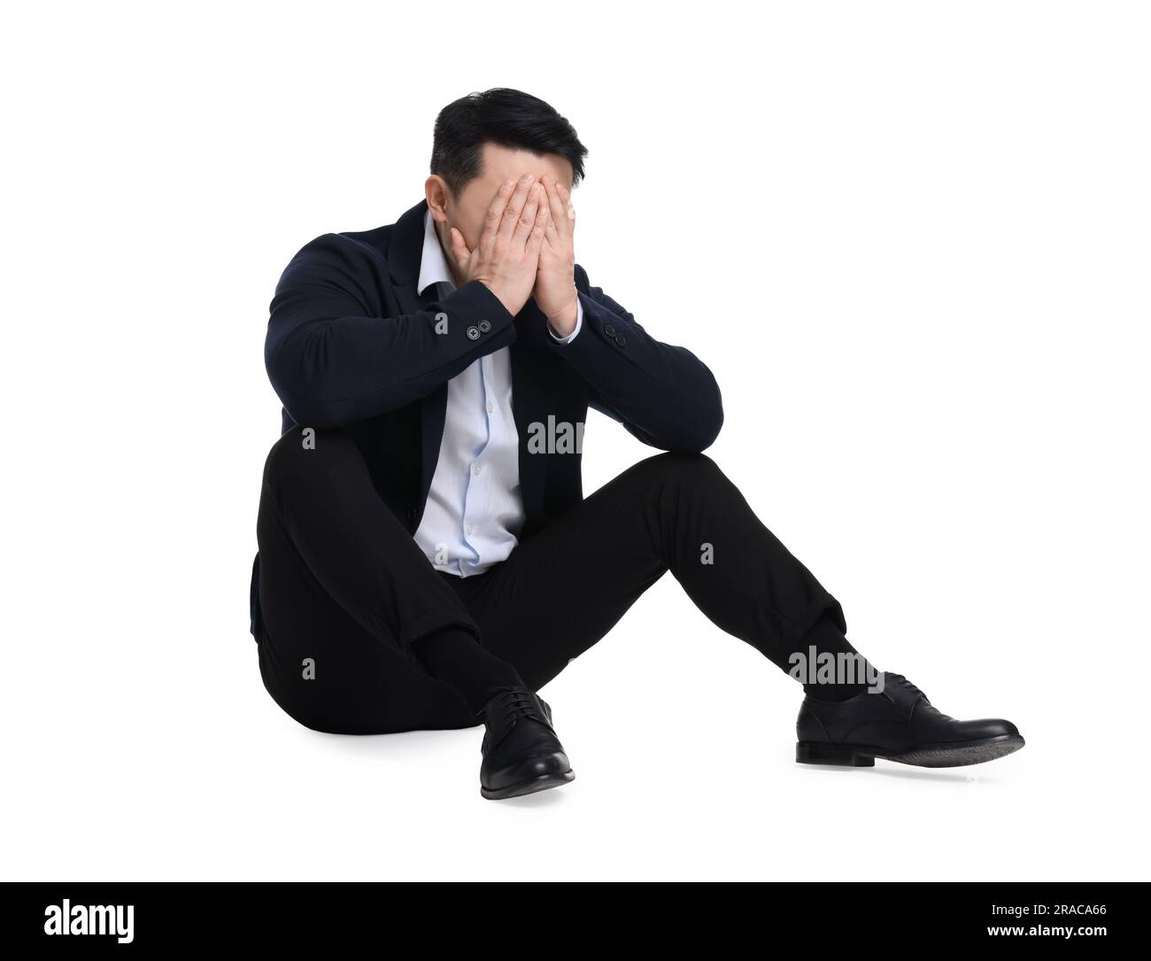 Tired businessman in suit sitting on white background Stock Photo - Alamy