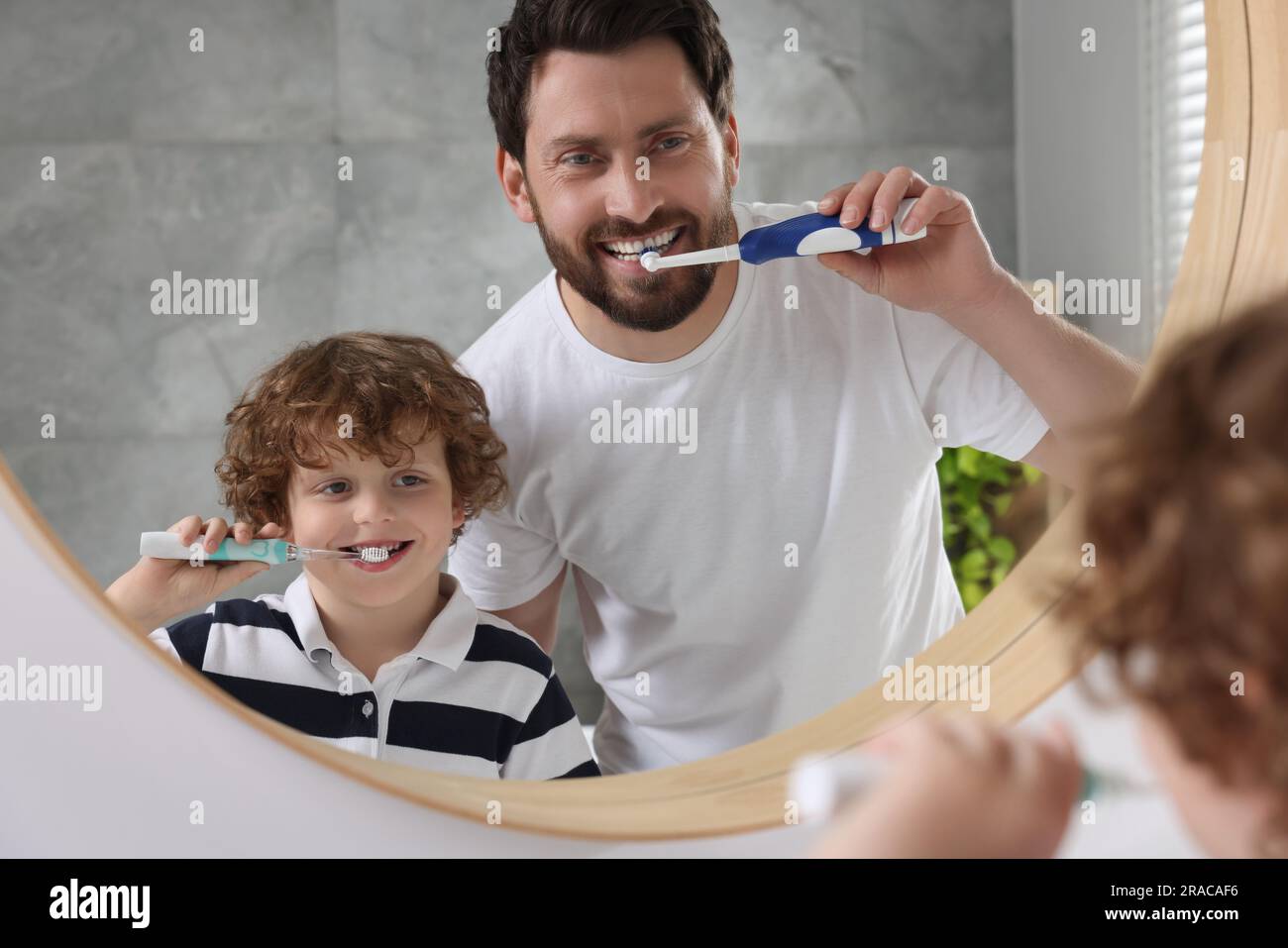 Father and his son brushing teeth together near mirror indoors Stock ...