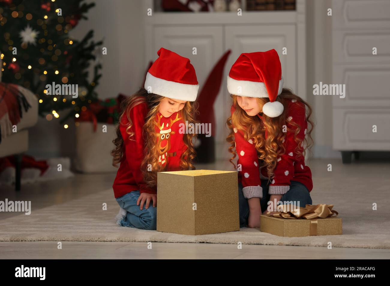 Cute little girls with Christmas gift at home. Magic atmosphere Stock ...