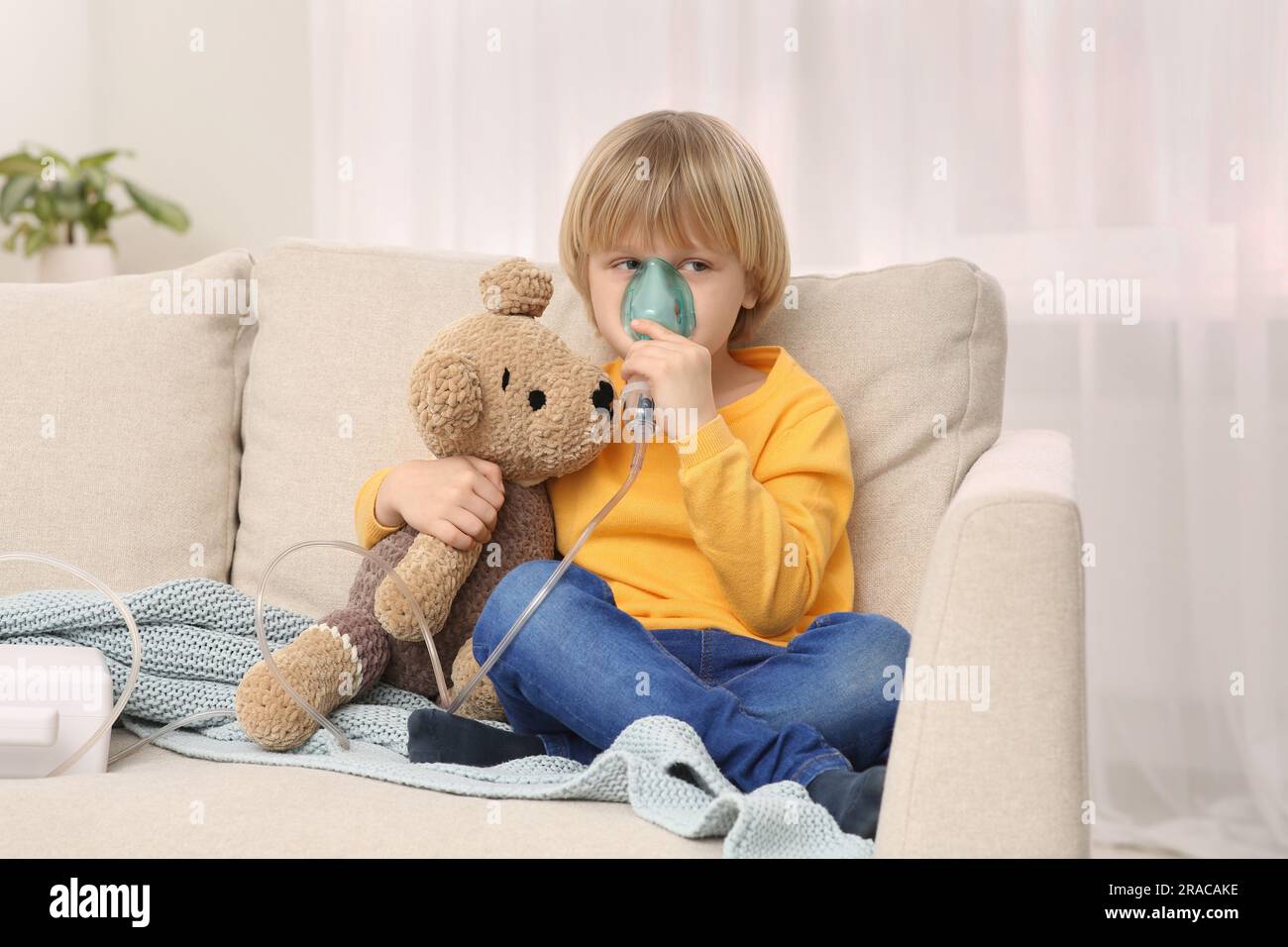 Boy with toy bear using nebulizer for inhalation at home Stock Photo ...