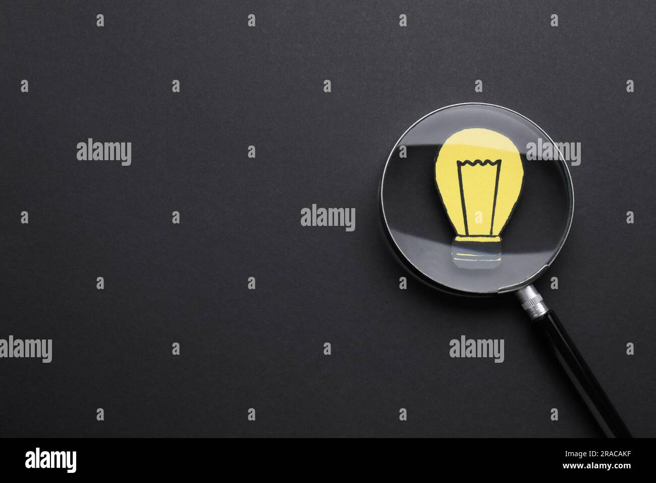 Magnifying glass over paper light bulb on dark background, top view ...