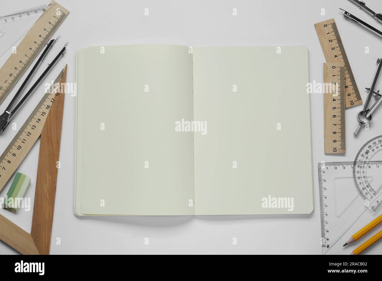 Different rulers, pencils and notebook on white background, top view ...