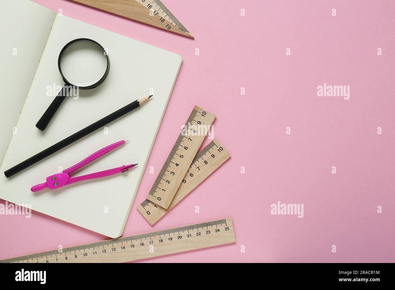 Different rulers, pencil, compass and magnifying glass on pink ...