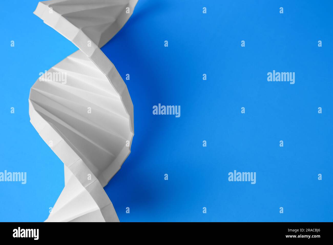 Paper model of DNA molecular chain on light blue background, above view ...