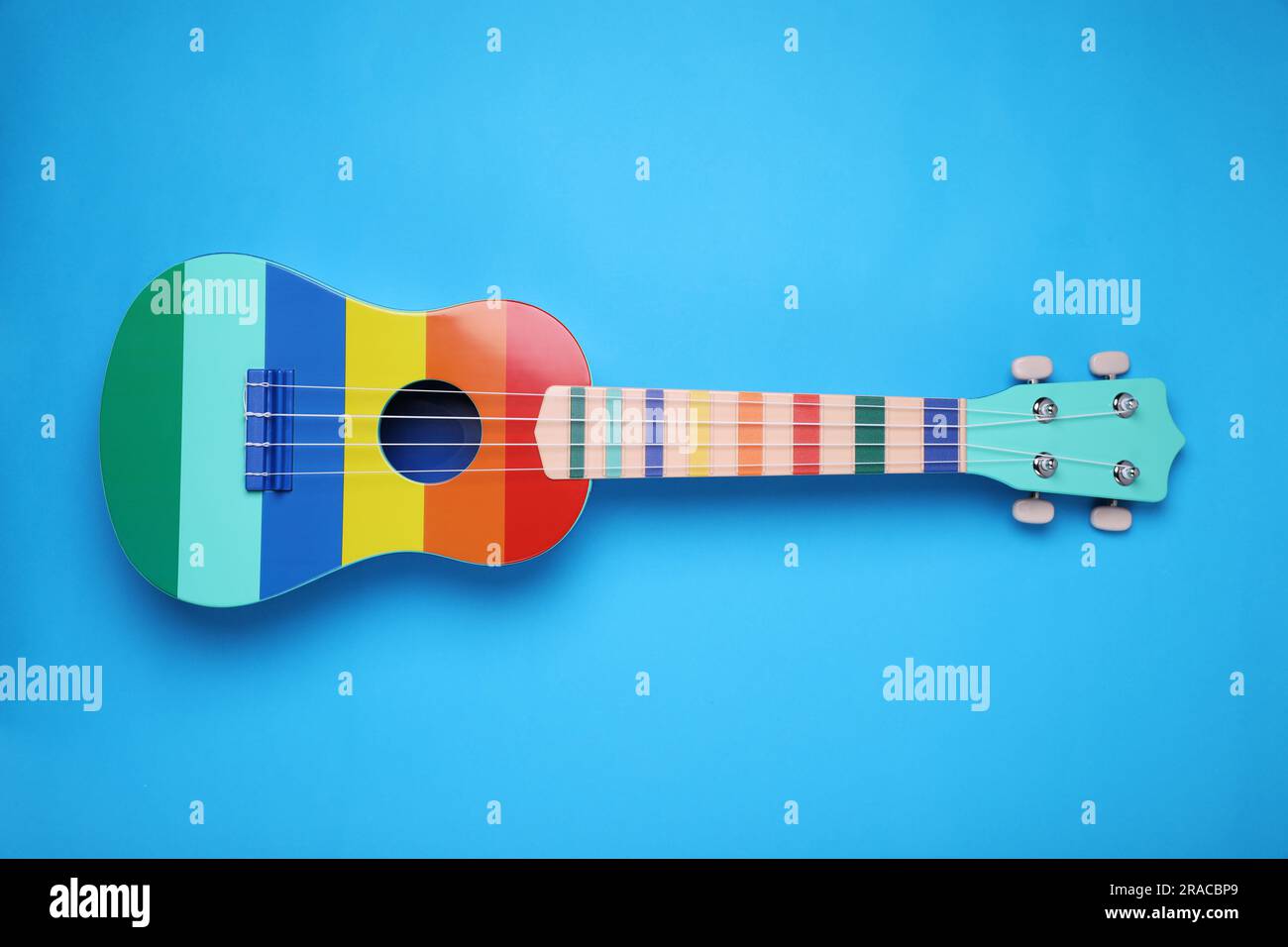 Colorful ukulele on light blue background, top view. String musical ...