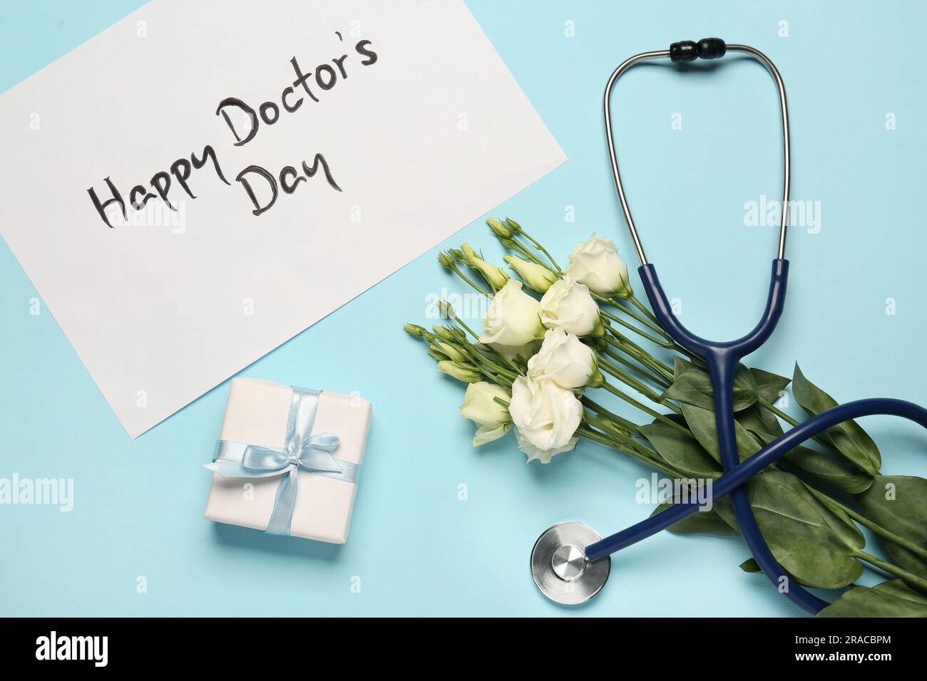 Card with phrase Happy Doctor's Day, stethoscope, gift box and eustoma ...