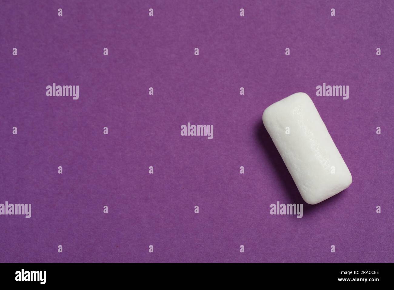 Tasty white chewing gum on purple background, top view. Space for text ...