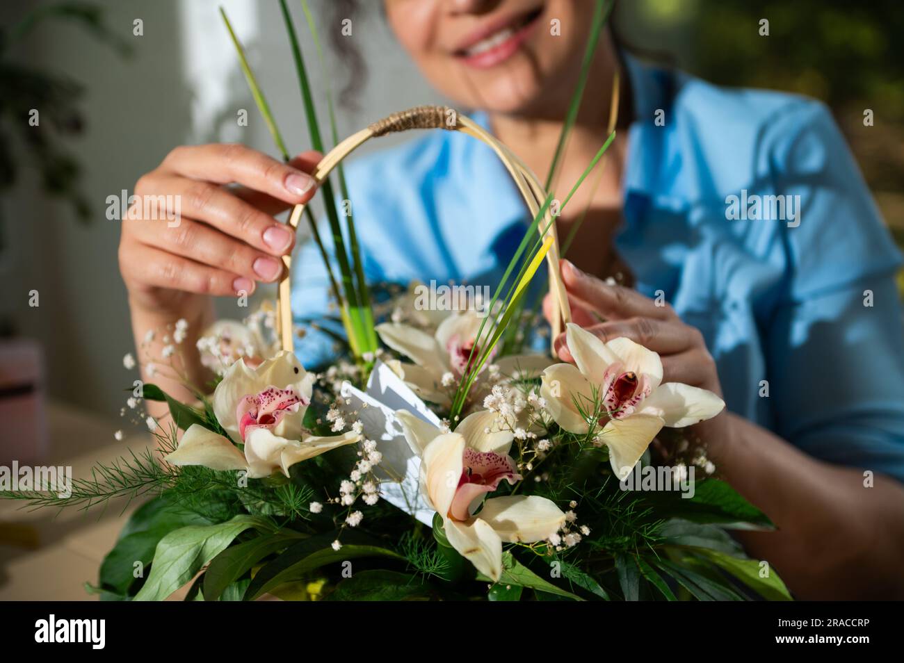 Beautiful flower arrangement in wicker basket in the hands of a blurred ...