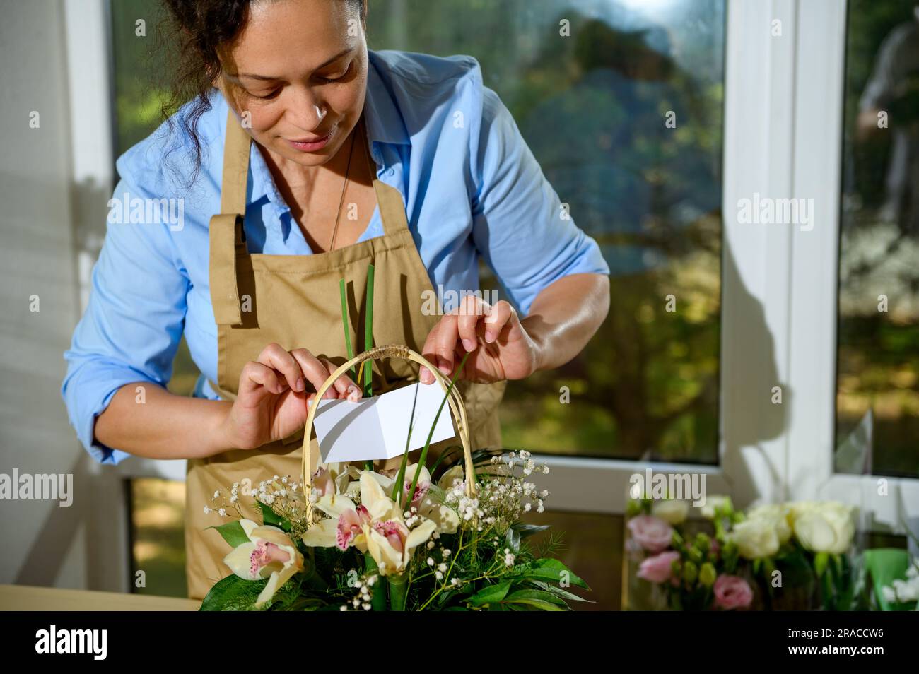 Close-up female florist inserting a white empty congratulatory card ...