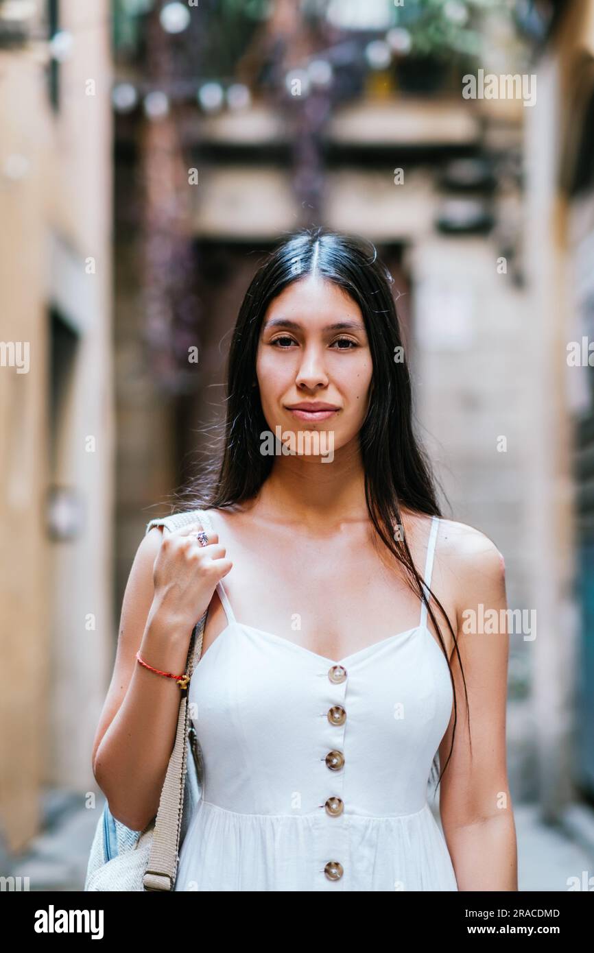 Latin American woman in white dress with backpack on shoulder looking ...