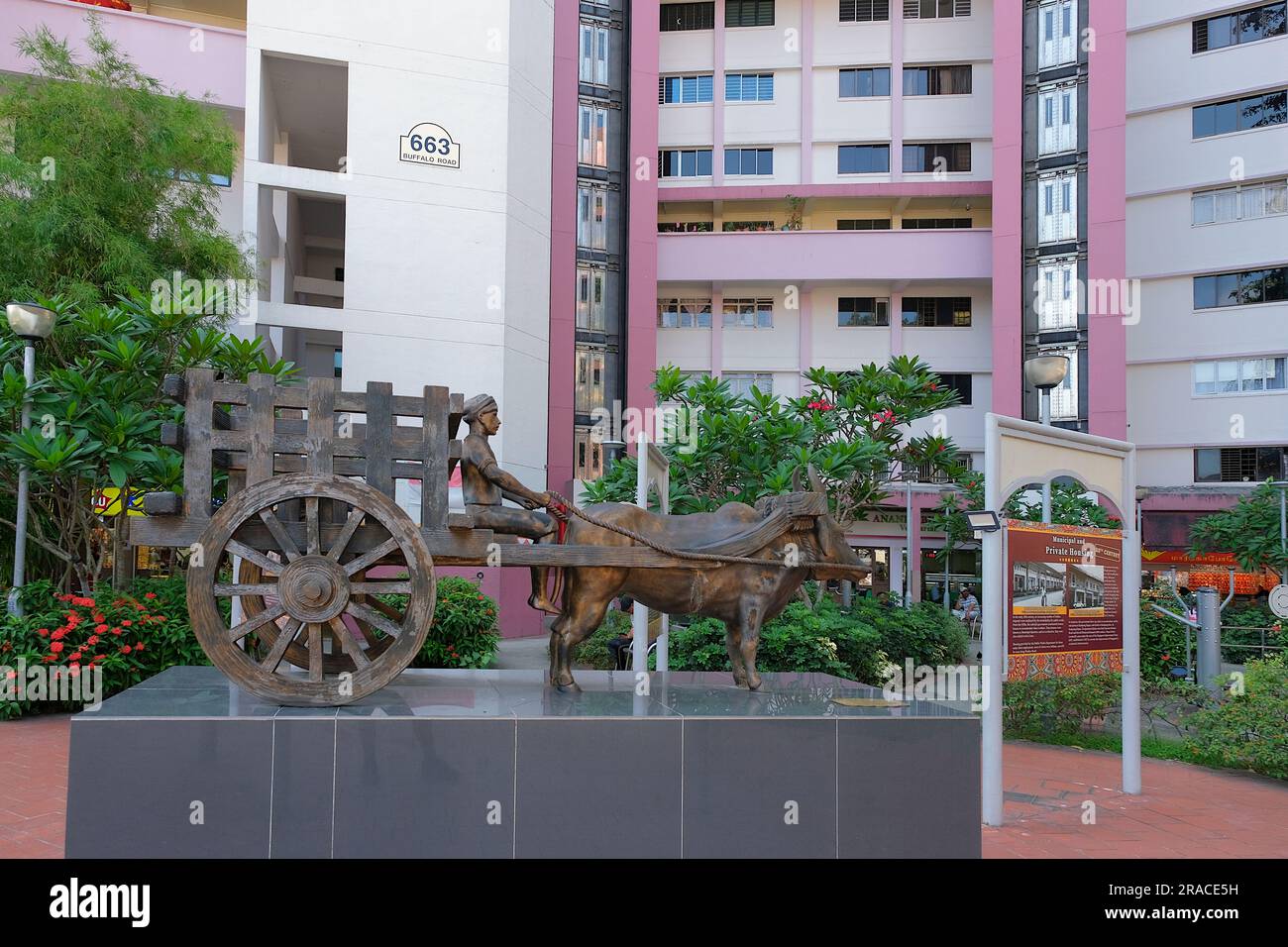 Statue of man sitting on bullock cart at the foot of block of flats ...