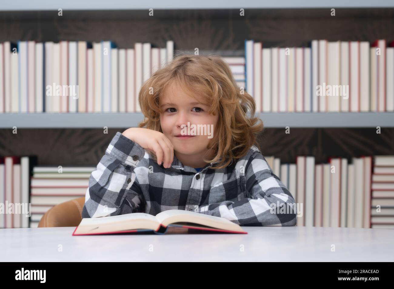 Child in the library reads books. Schoolkid choosing book in school ...