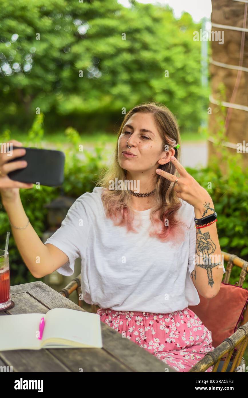 Cute woman taking a photo selfie and drinking tea in summer garden ...